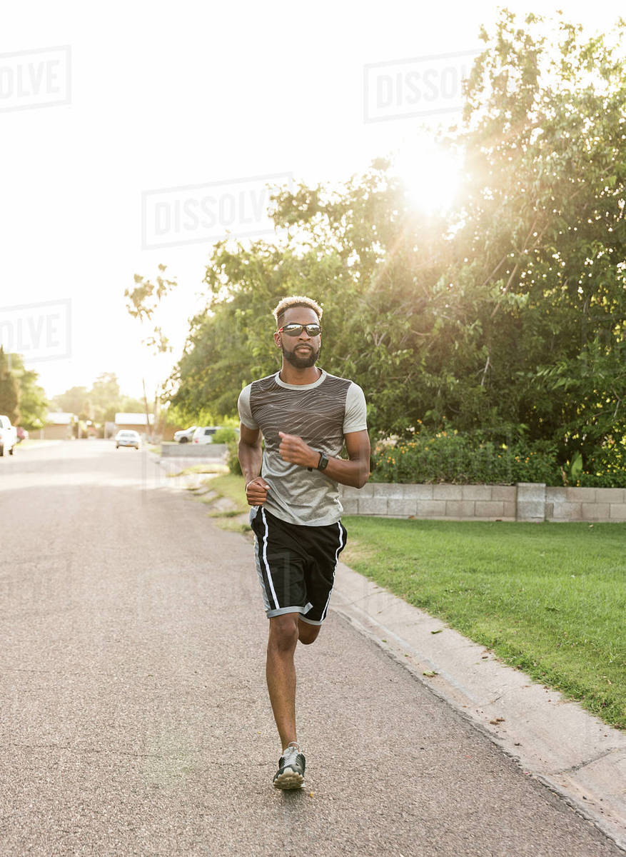 Black man running on street in neighborhood - Stock Photo - Dissolve