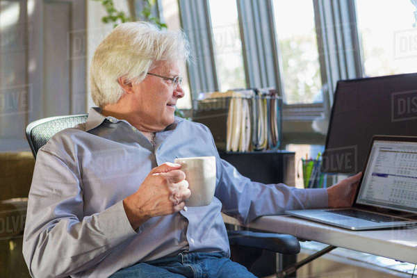 Caucasian man drinking coffee and using laptop - Royalty-free Stock ...