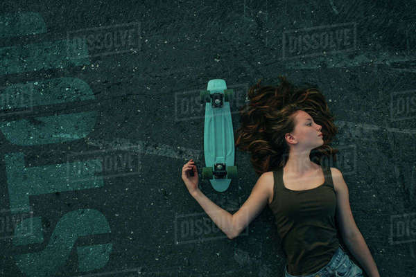 Caucasian teenage girl laying on pavement with skateboard - Stock Photo ...