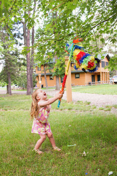 Laughing Caucasian girl hitting pinata outdoors - Stock Photo - Dissolve