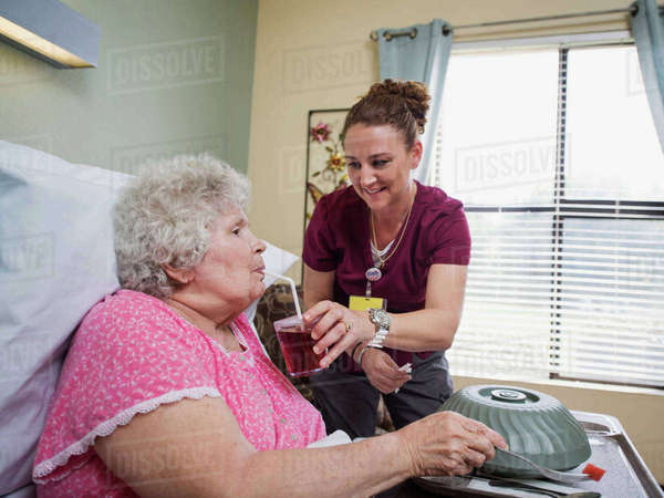Caucasian nurse feeding patient in hospital bed - Royalty-free Stock ...