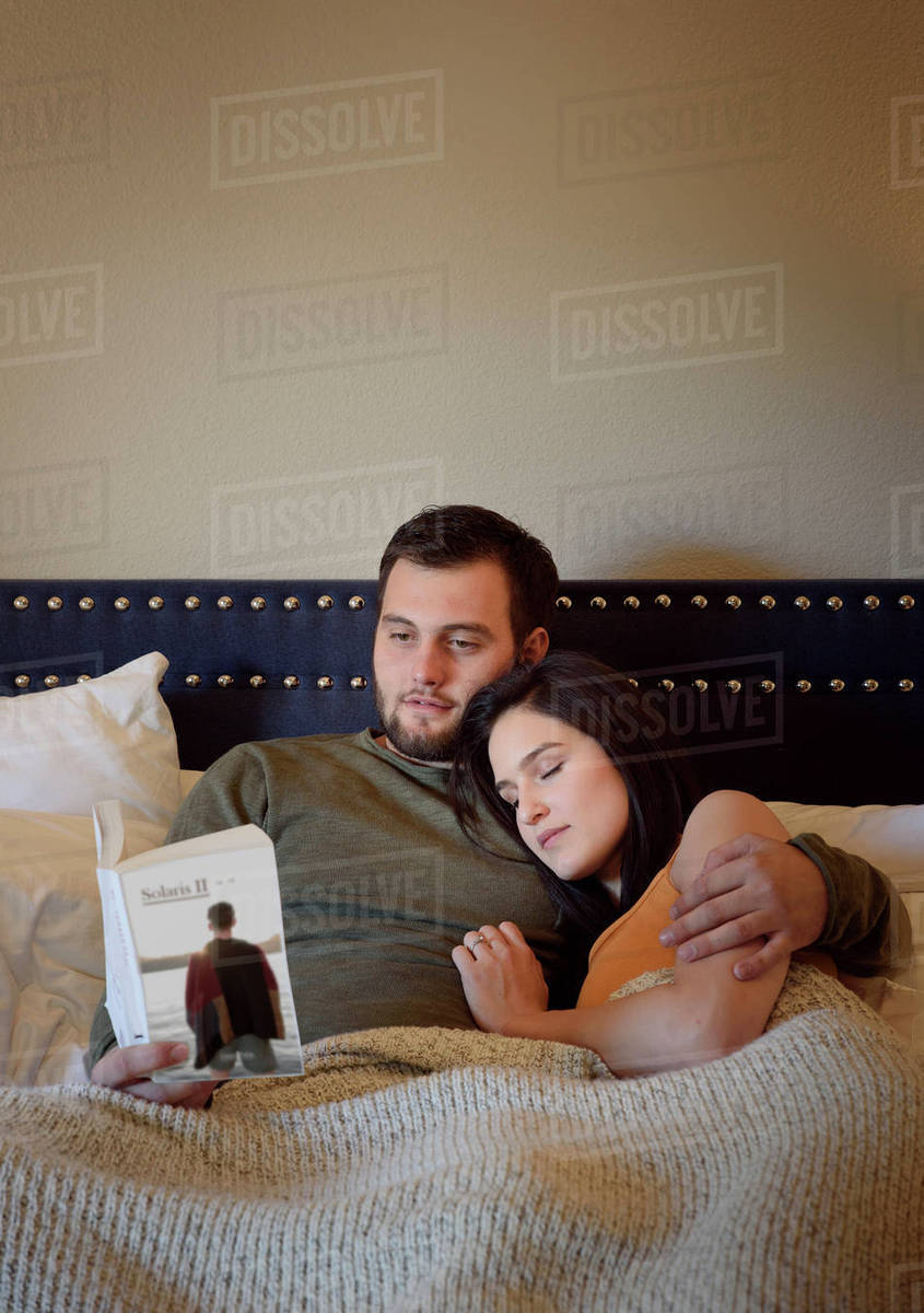 Caucasian man reading book in bed cuddling with woman - Stock Photo ...