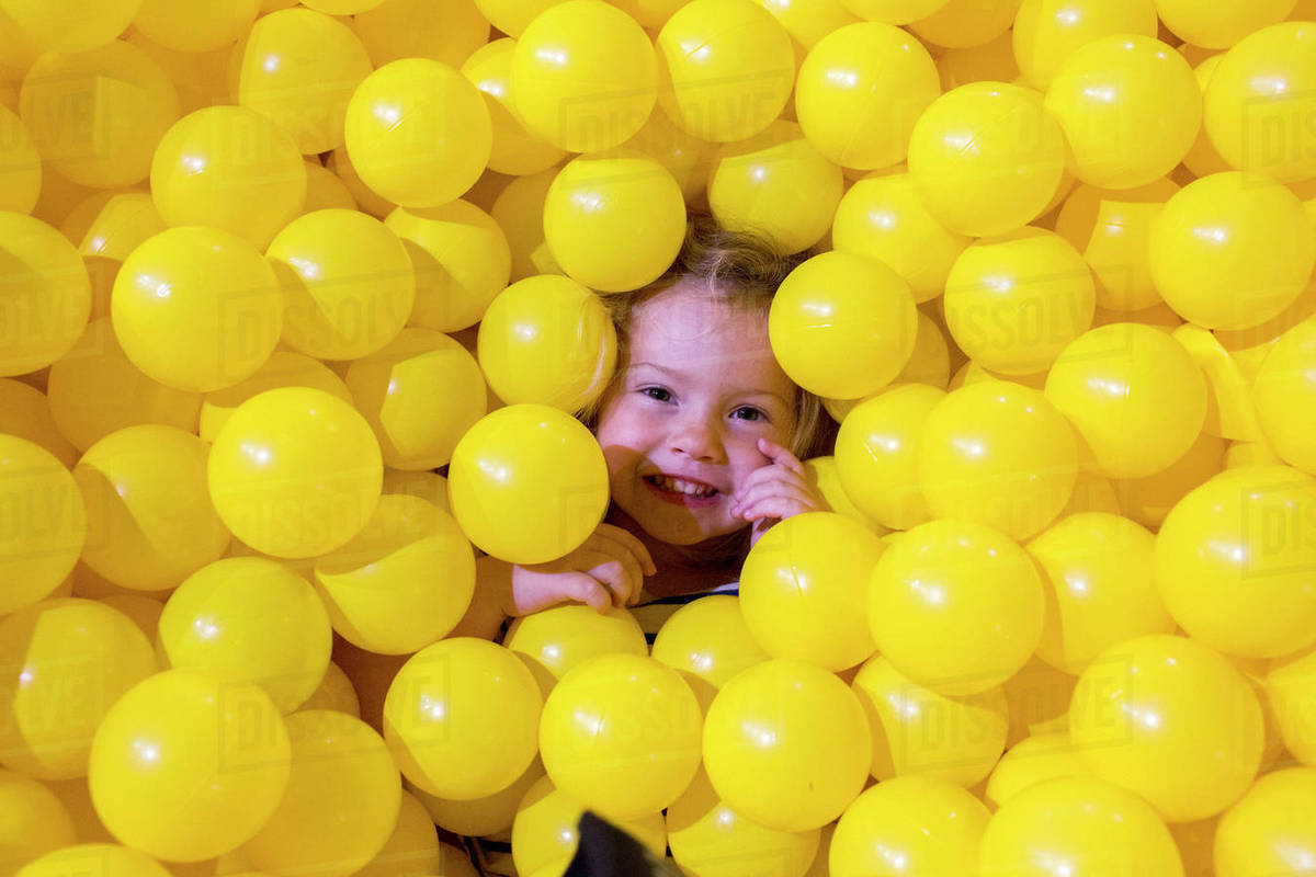 Caucasian girl laying in pile of yellow balls - Royalty-free Stock ...