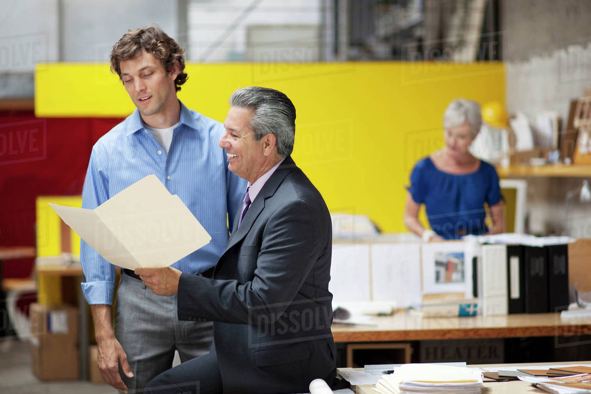Businessmen reading file folder in office - Stock Photo - Dissolve