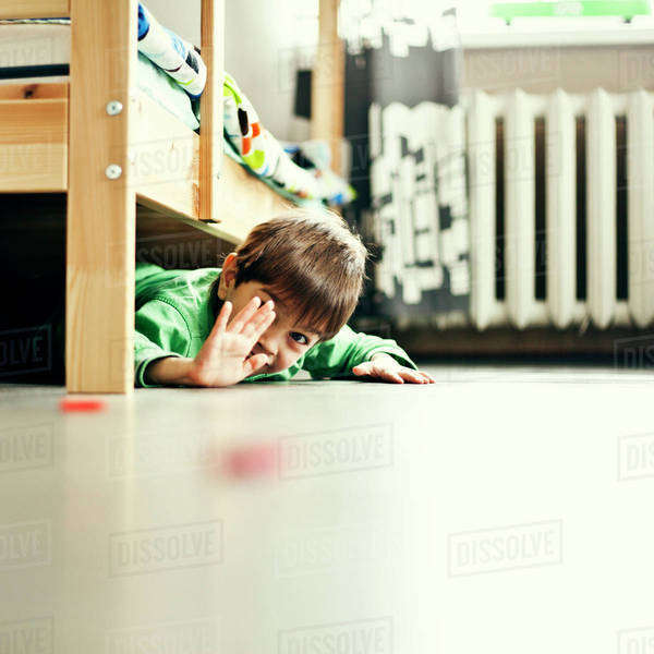 Boy crawling out from under bed - Stock Photo - Dissolve