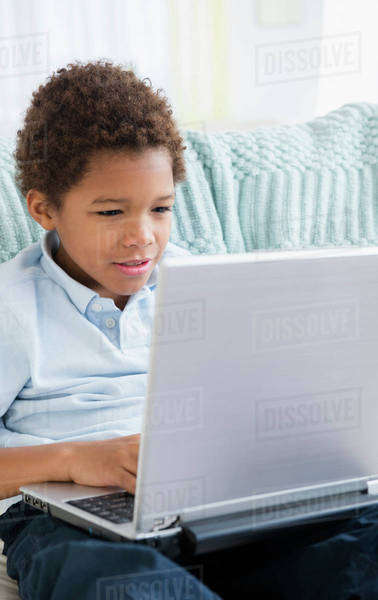 Black boy using laptop in living room - Stock Photo - Dissolve