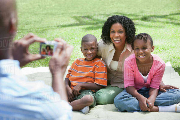 Family taking picture together on picnic blanket - Stock Photo - Dissolve