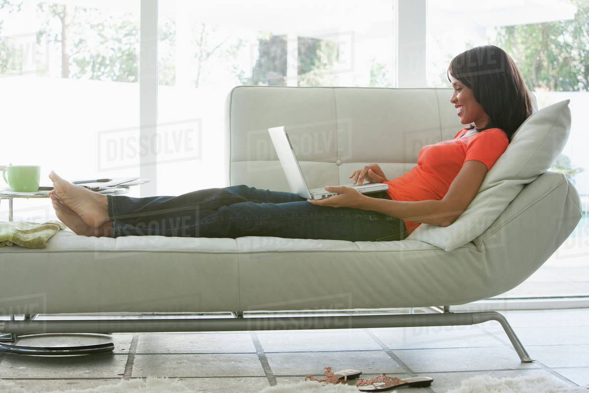 Woman using laptop on sofa - Royalty-free Stock Photo | Dissolve