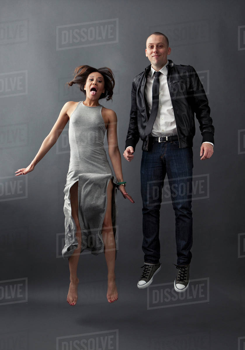 Couple jumping together in studio - Royalty-free Stock Photo | Dissolve
