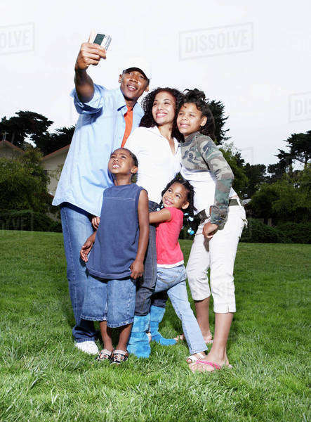 Family taking picture together in park - Stock Photo - Dissolve