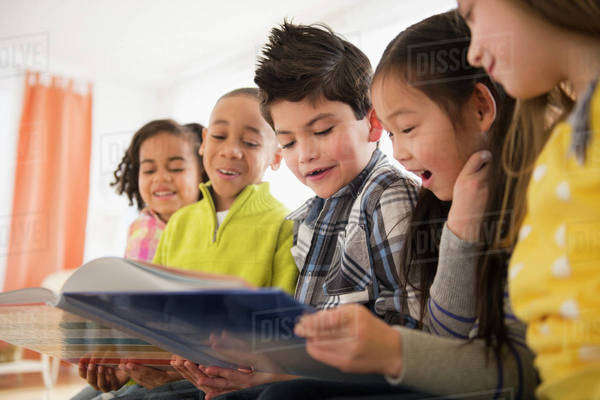 Children reading together in living room - Stock Photo - Dissolve