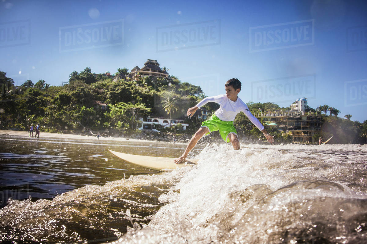 Mixed race boy surfing in ocean - Royalty-free Stock Photo | Dissolve