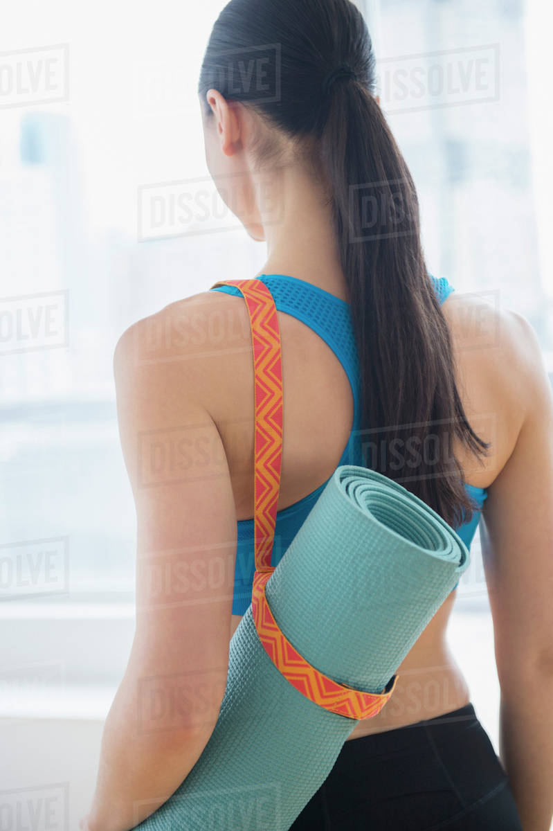 Caucasian woman carrying yoga mat - Stock Photo - Dissolve