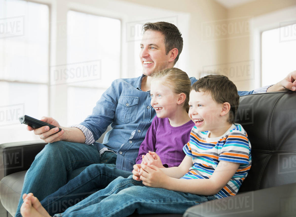 Caucasian father and children watching television on sofa - Royalty ...