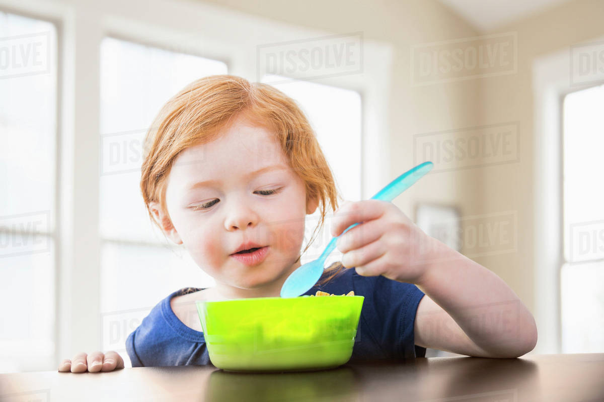Caucasian girl eating at table - Royalty-free Stock Photo | Dissolve