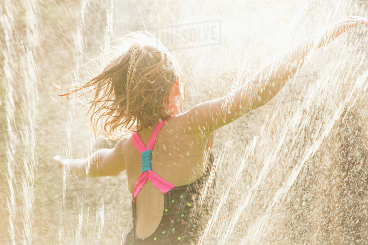 Girl standing in sprinkler - Royalty-free Stock Photo | Dissolve
