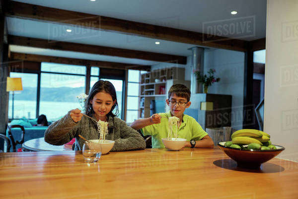 Mixed race children eating noodles at table - Royalty-free Stock Photo ...