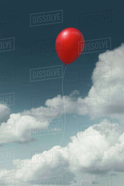 Red balloon floating in cloudy sky - Stock Photo - Dissolve
