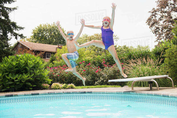 Caucasian children jumping into swimming pool - Stock Photo - Dissolve