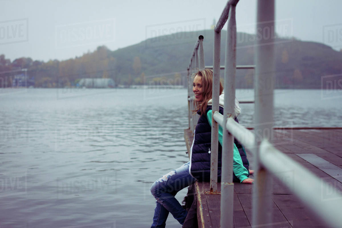 Caucasian woman sitting on dock over still lake - Royalty-free Stock ...