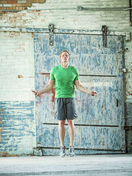 Caucasian man jumping rope in warehouse - Stock Photo - Dissolve