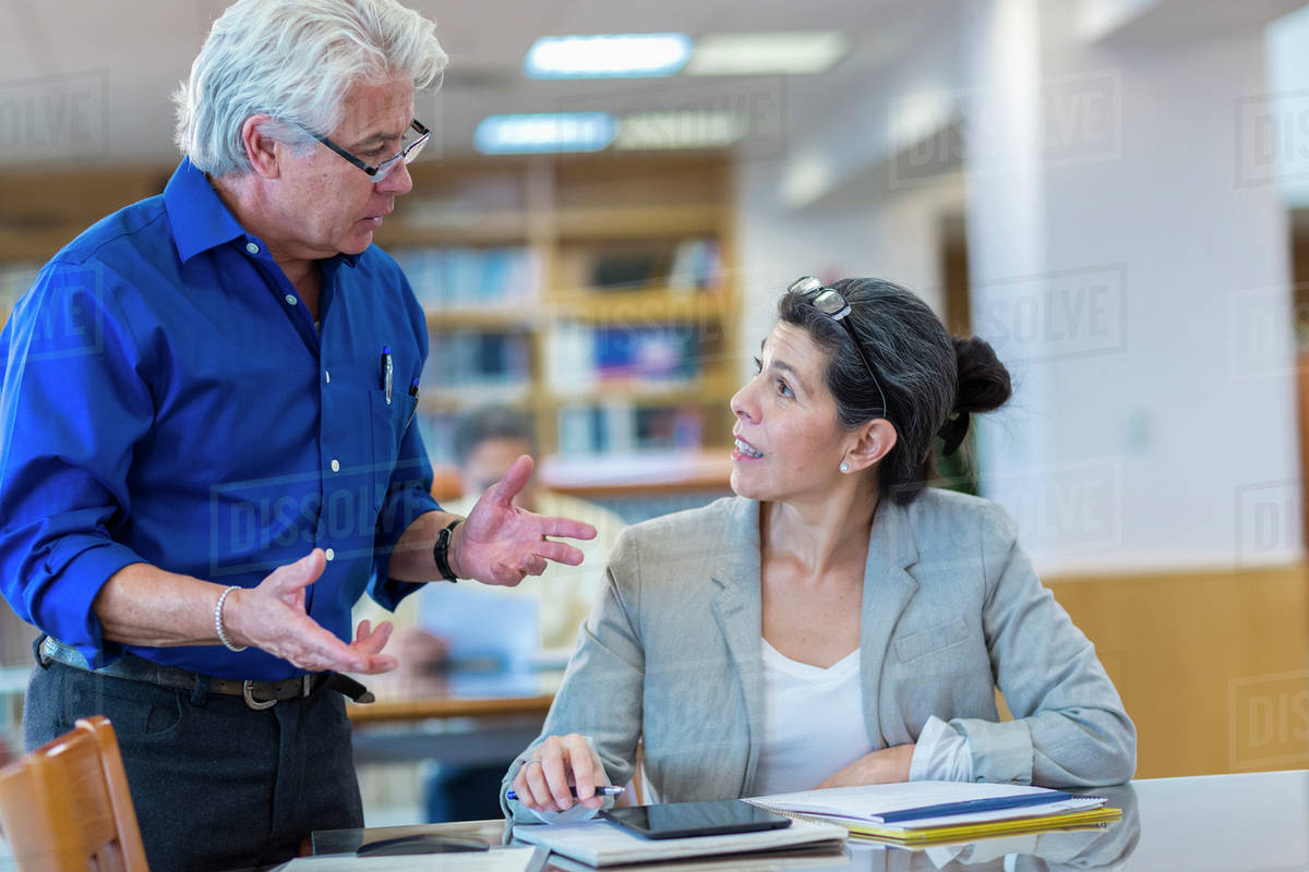 Teacher helping adult student in library - Royalty-free Stock Photo ...