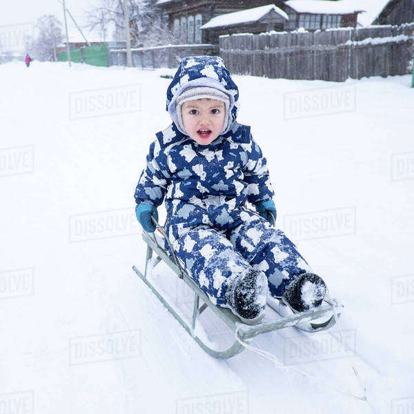 Mari boy in snow suit sledding on neighborhood street - Stock Photo ...