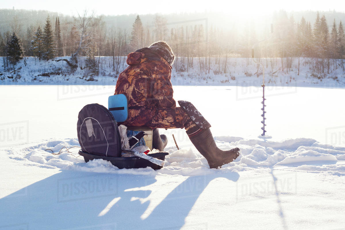 Mari man ice fishing in snowy field - Royalty-free Stock Photo | Dissolve