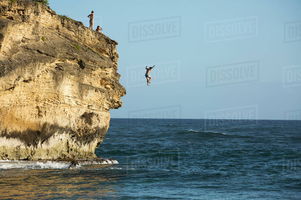 Divers jumping off cliff into ocean - Royalty-free Stock Photo | Dissolve