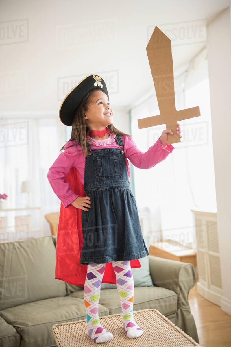 Hispanic girl playing with cape and sword - Stock Photo - Dissolve