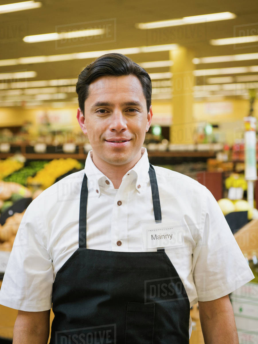 Hispanic worker smiling in grocery store - Royalty-free Stock Photo ...