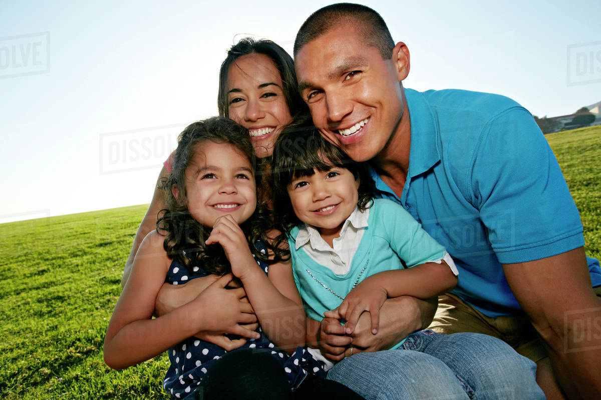 Family smiling together in field - Royalty-free Stock Photo | Dissolve