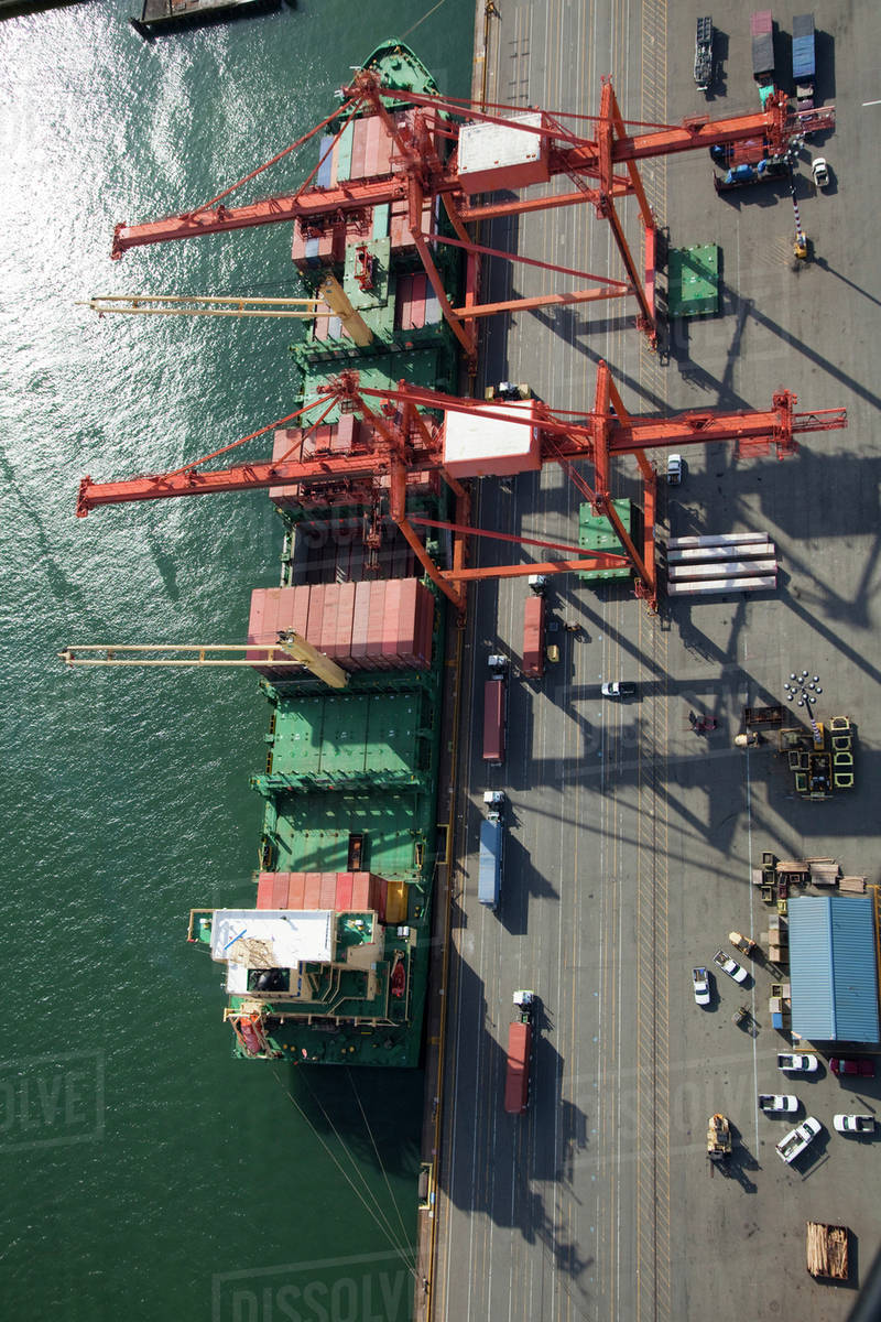 Aerial view of cranes unloading container ship at commercial dock ...