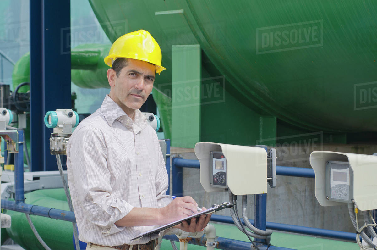 Hispanic worker checking machinery - Royalty-free Stock Photo | Dissolve