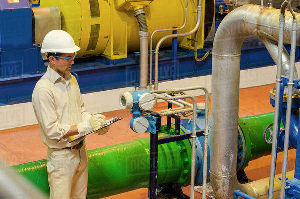 Hispanic worker checking machinery - Royalty-free Stock Photo | Dissolve