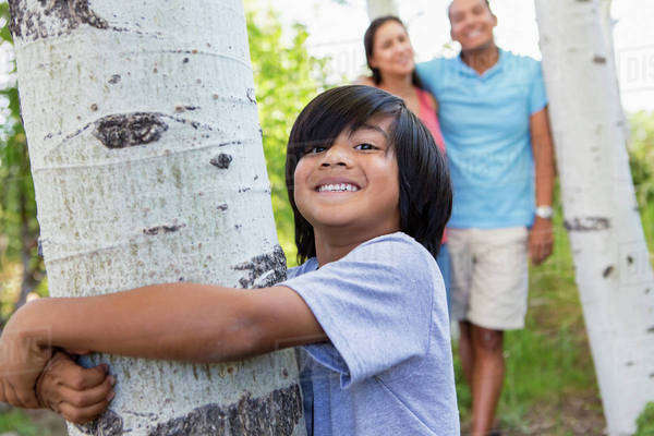 Boy hugging tree outdoors - Royalty-free Stock Photo | Dissolve