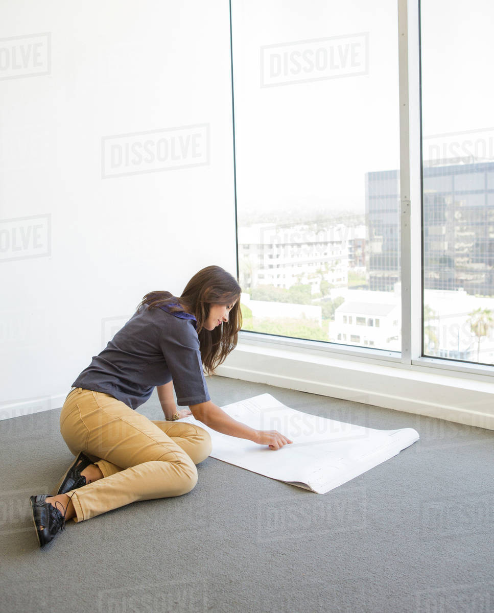 Woman reading blueprints in empty office - Royalty-free Stock Photo ...
