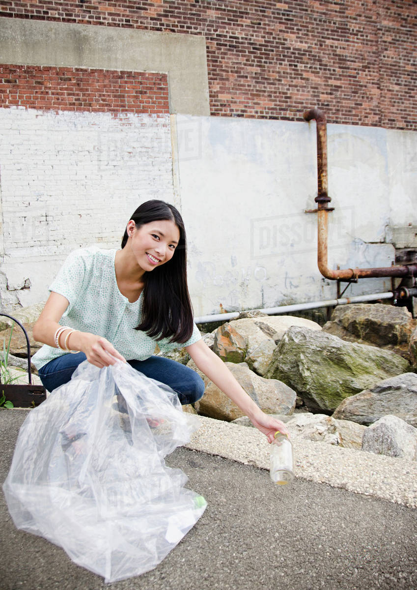 Asian woman picking up litter - Royalty-free Stock Photo | Dissolve