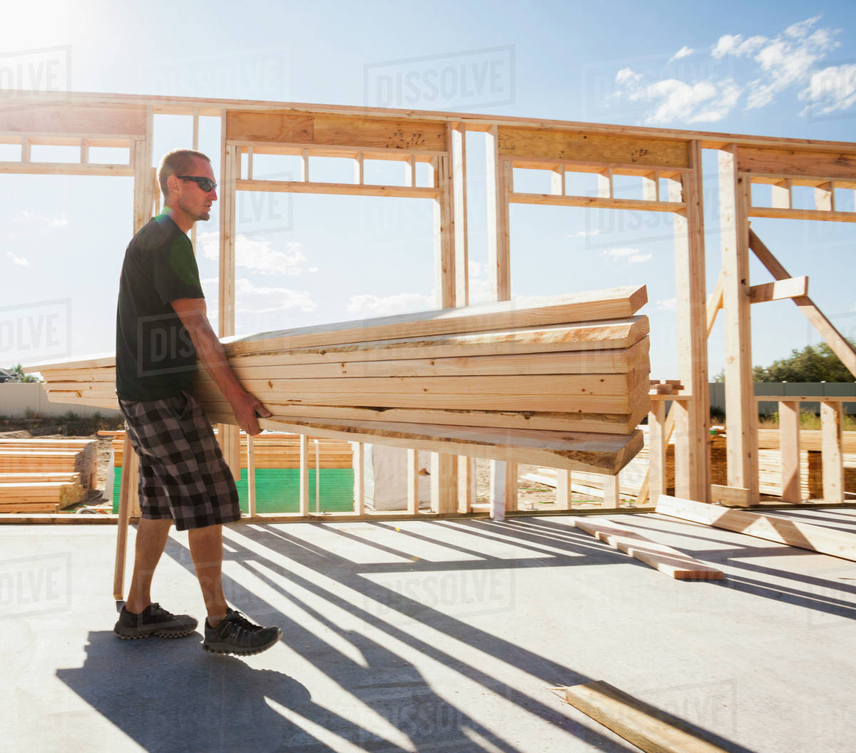 Caucasian man carrying lumber on construction site - Royalty-free Stock ...