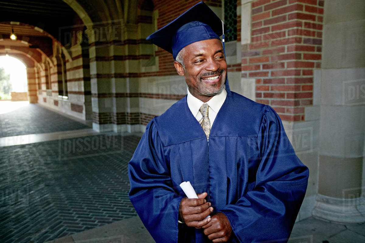 Smiling Black man holding graduation diploma - Stock Photo - Dissolve