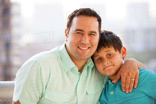 Hispanic father hugging son and smiling - Stock Photo - Dissolve