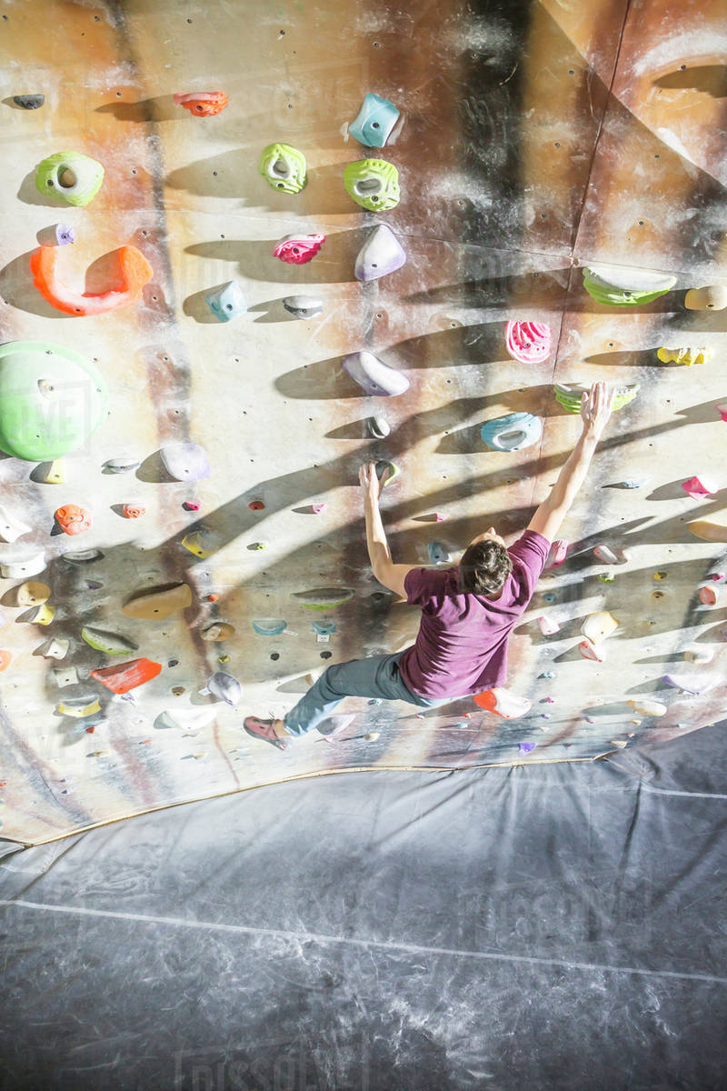 High angle view of athlete climbing rock wall in gym - Stock Photo ...