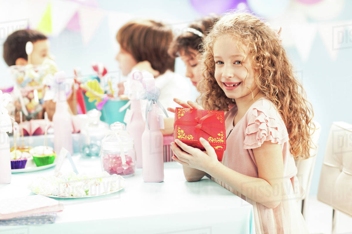 Girl holding wrapped gift at birthday party - Royalty-free Stock Photo ...