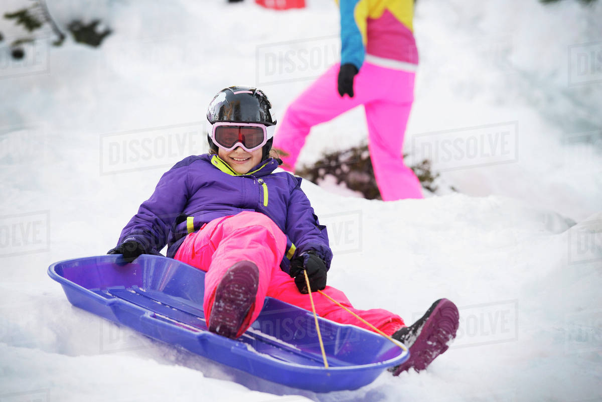 Mixed race girl sledding on snowy hillside - Royalty-free Stock Photo ...
