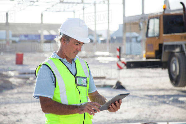 Caucasian construction worker using digital tablet at construction site ...
