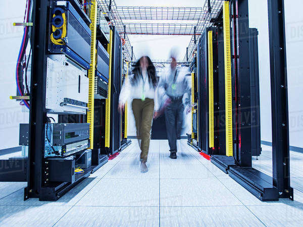 Blurred view of technicians walking in server room - Stock Photo - Dissolve