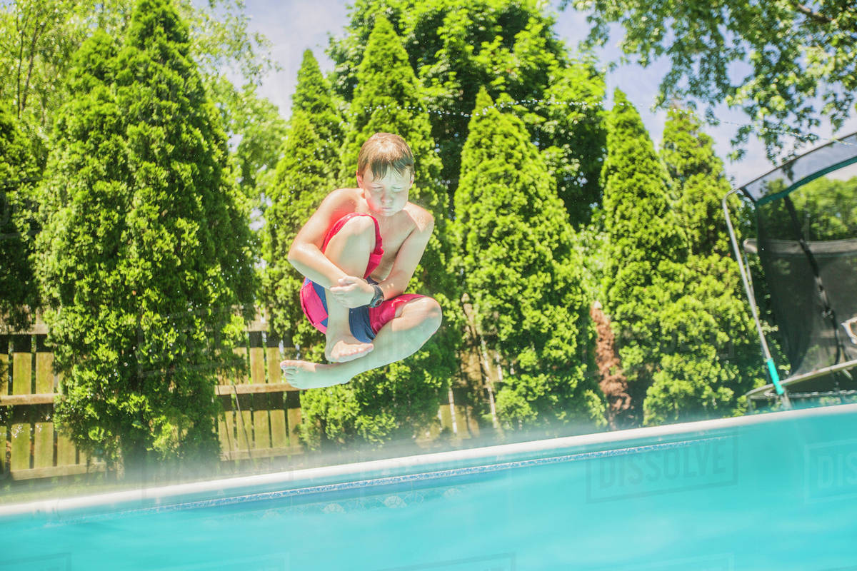 Caucasian boy jumping into swimming pool - Stock Photo - Dissolve