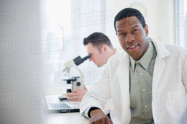Scientist sitting at table in lab - Royalty-free Stock Photo | Dissolve