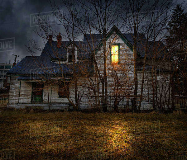 Glowing window casting light in backyard - Stock Photo - Dissolve