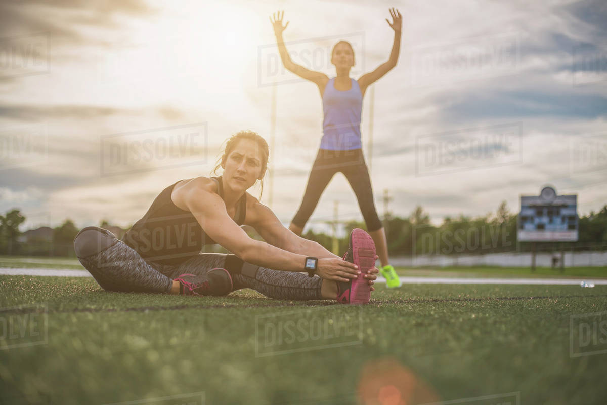 Athletes stretching on sports field - Stock Photo - Dissolve